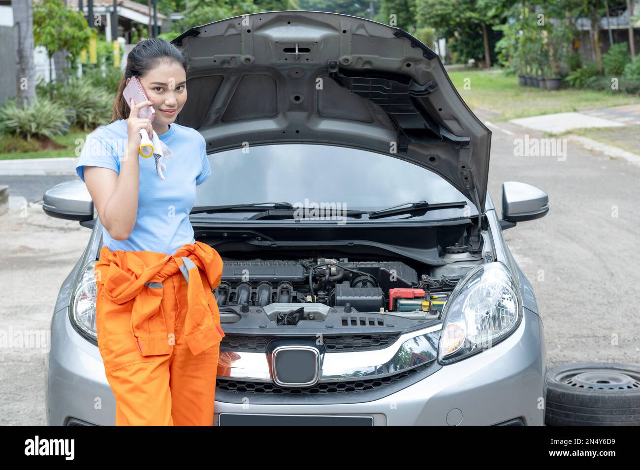 Asian women car technicians in uniform standing in front of breakdown ...