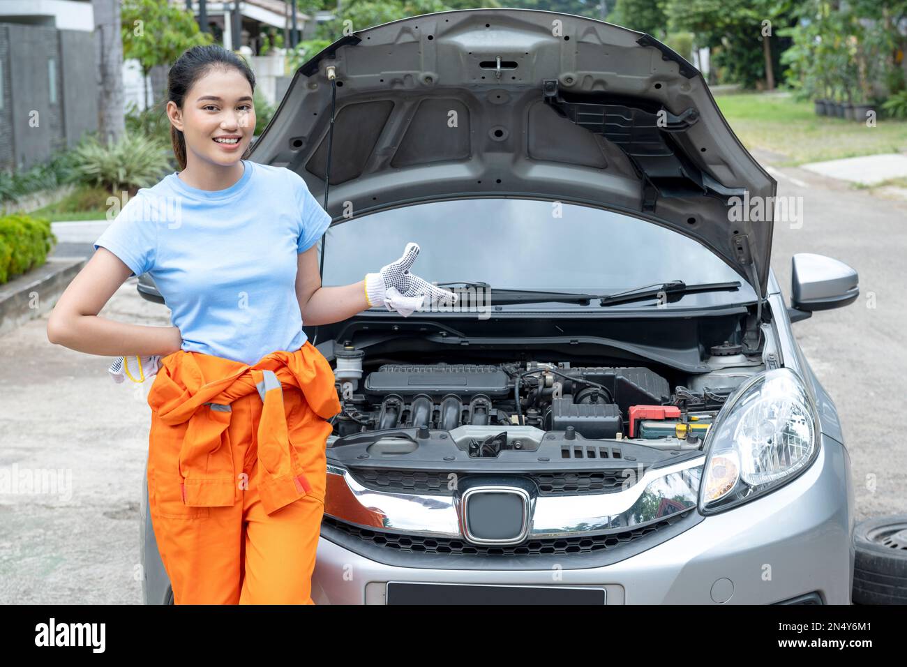Asian women car technicians in uniform standing while pointing ...