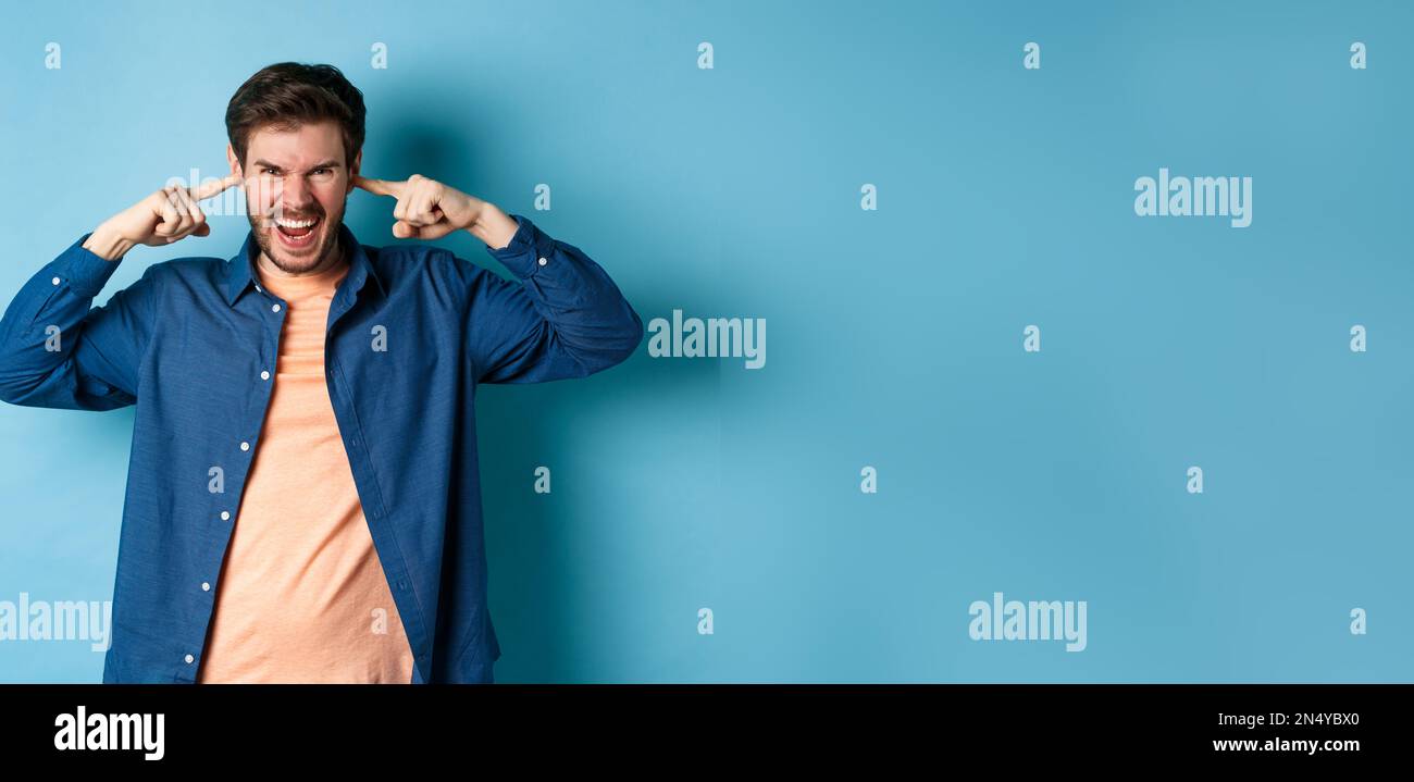 Angry young man shut ears to block annoying sound and shouting at ...