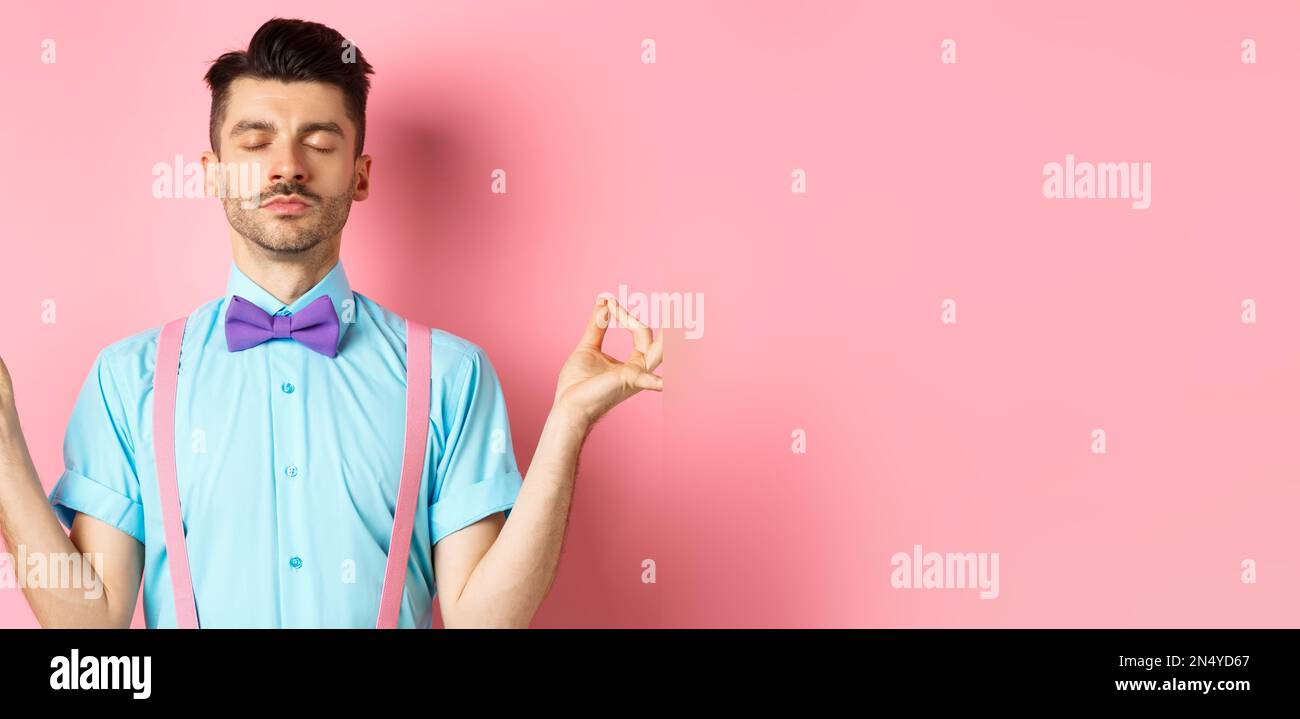 Young guy in bow-tie standing calm and peaceful, meditating with hands ...