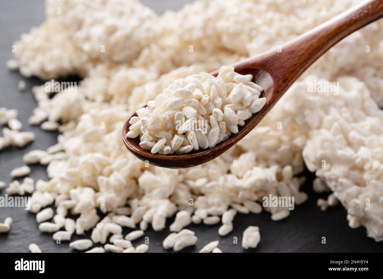 Closeup of rice koji and wooden spoon placed on black background. Koji ...