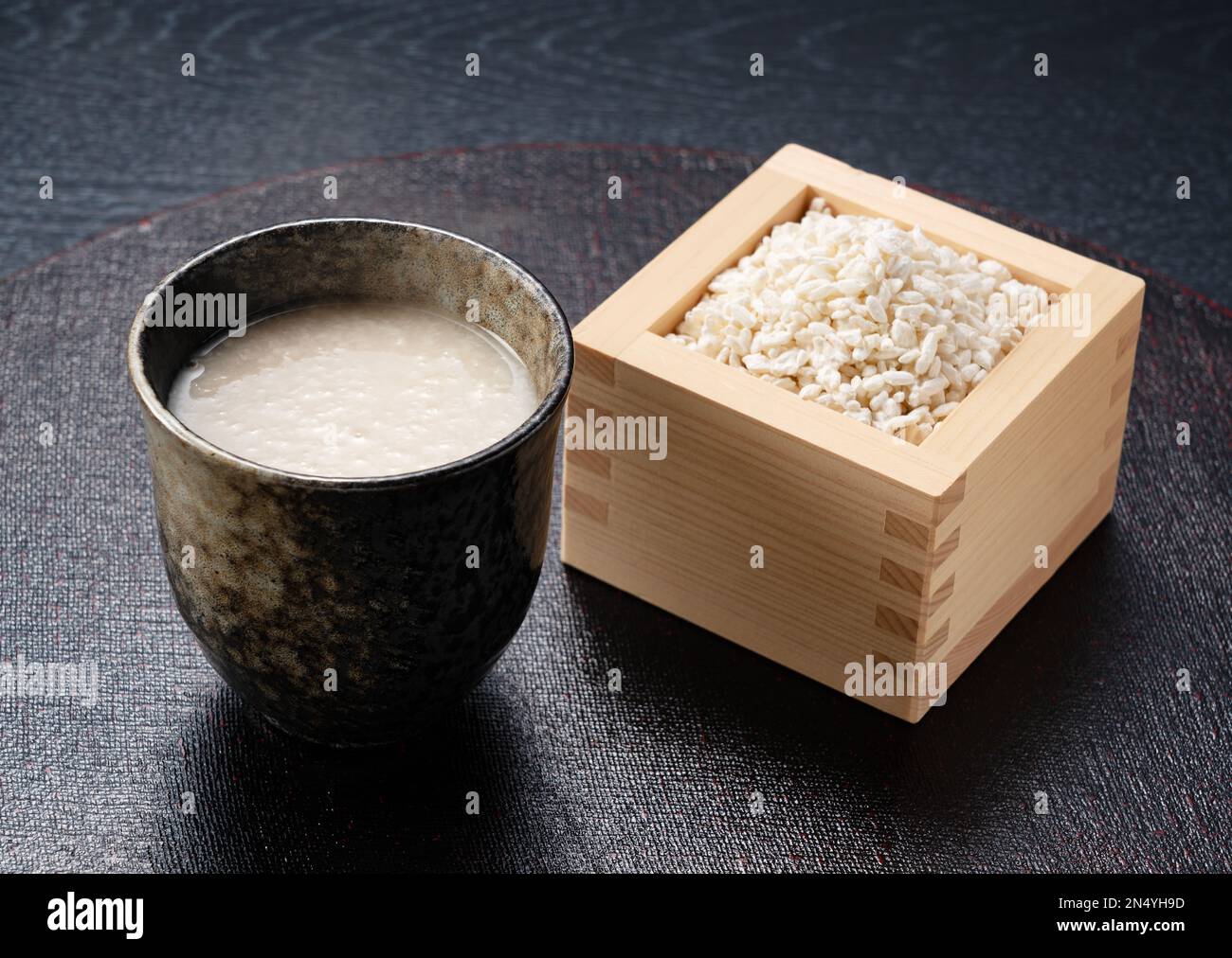 Amazake placed against a black background and rice koji in a masu box ...