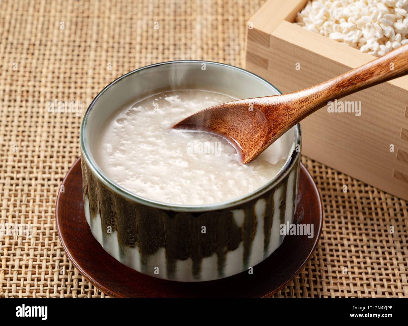 Amazake and a wooden spoon on the table. Amazake is a traditional ...