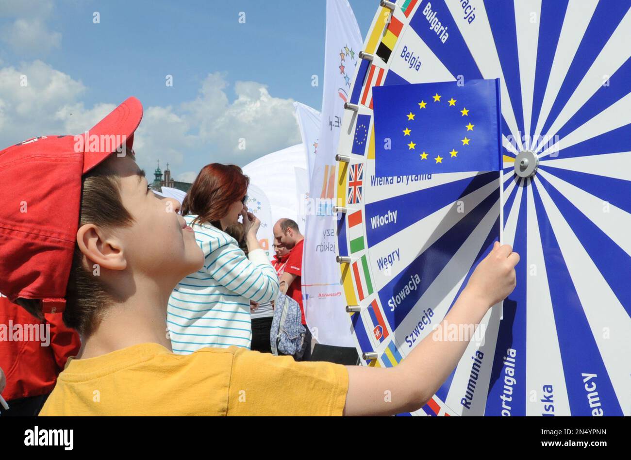 A boy holding a EU flag looks at a wheel with the names of all European ...