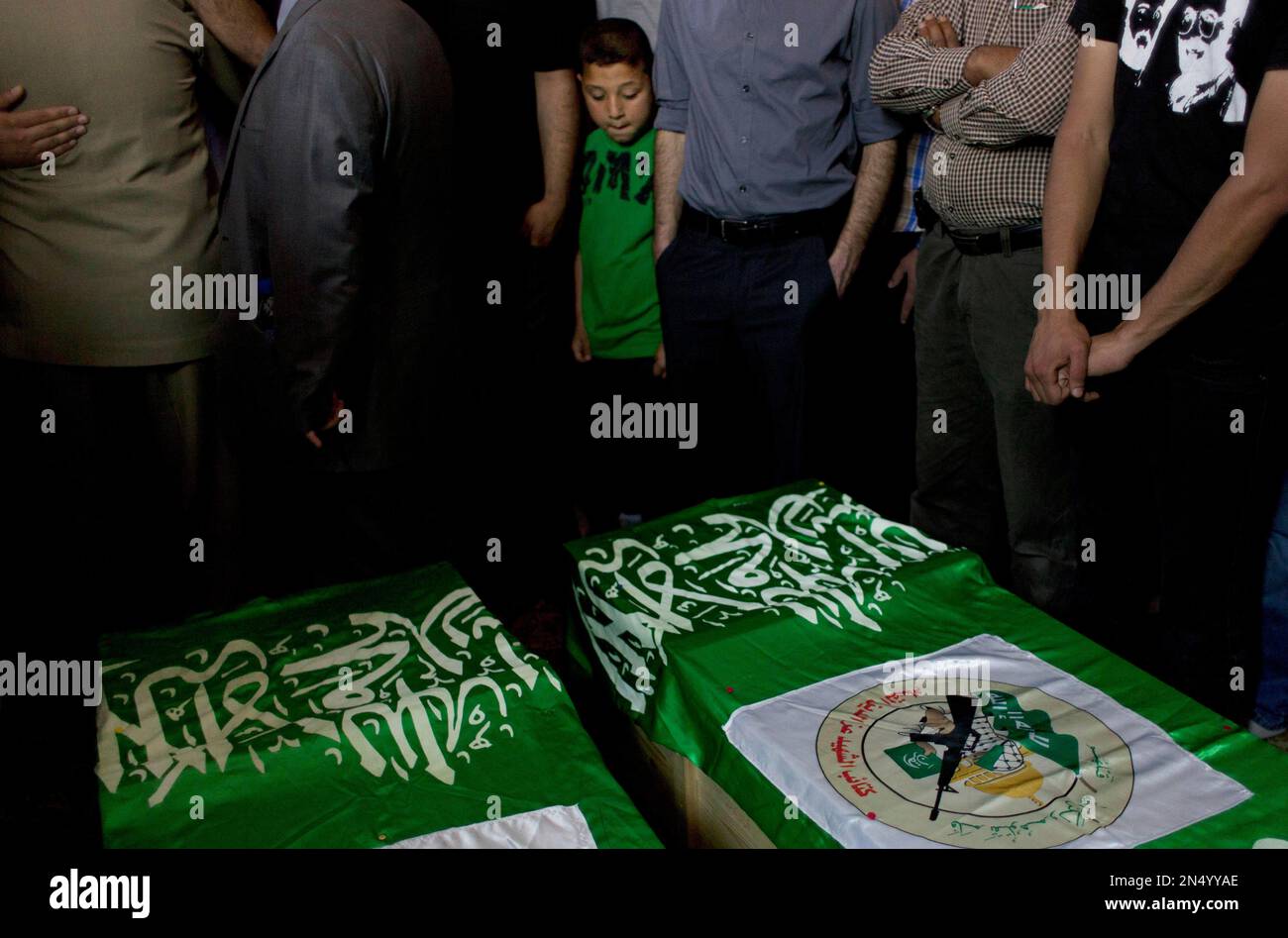 A Palestinian child stands in front of the coffins of two Palestinian ...