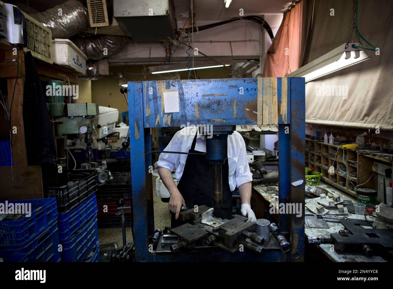 An ultra-Orthodox Jewish worker places a sets of tefillin in a presser ...