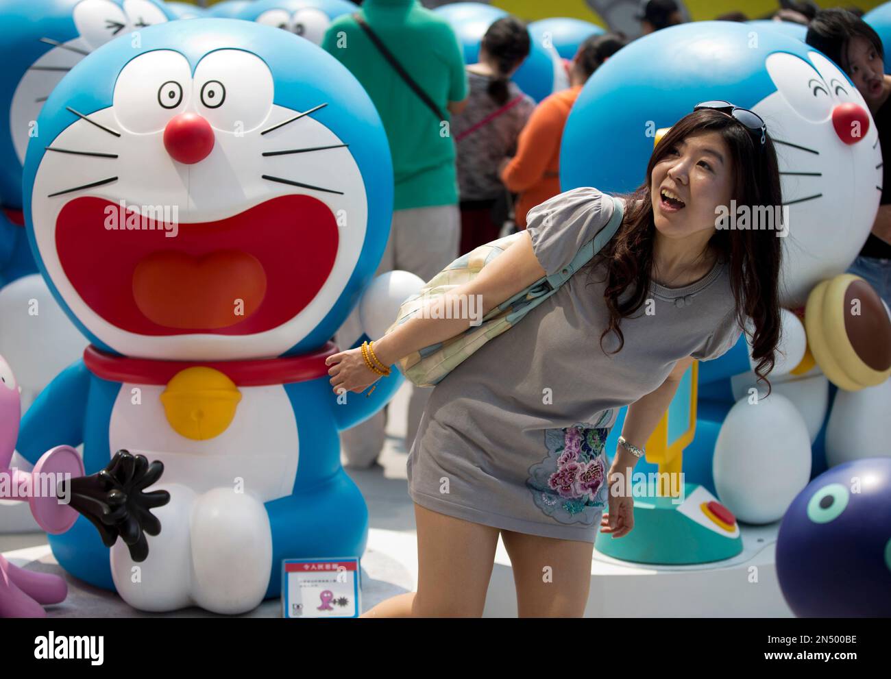 A woman poses next to a model of Doraemon, one of Japan's most popular ...