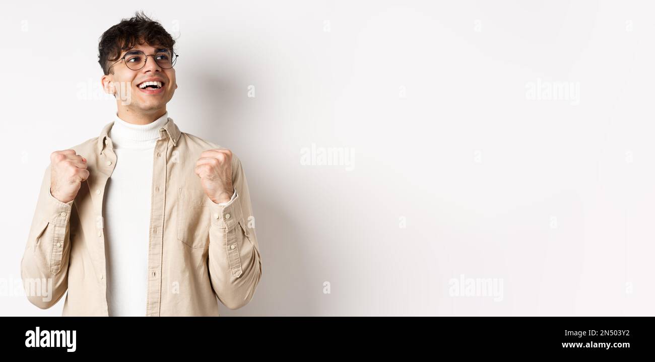 Lucky young man say yes with relieved face, smiling and making fist ...