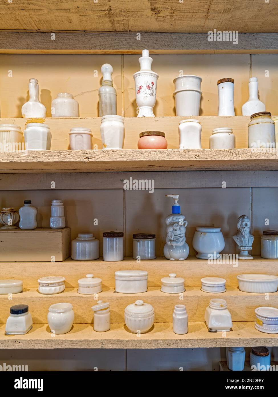 Collection of antique opal glass containers displayed on wooden shelves ...