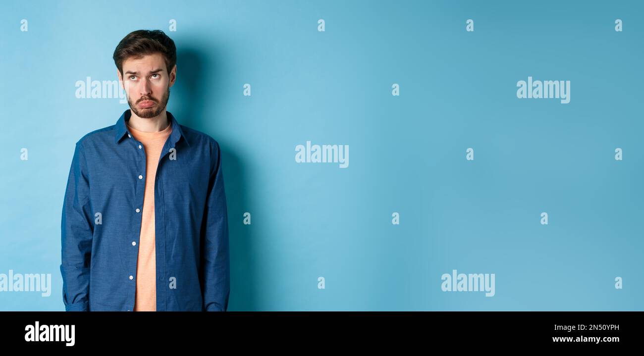 Sad man whining and sulking, looking up with upset face, standing on ...