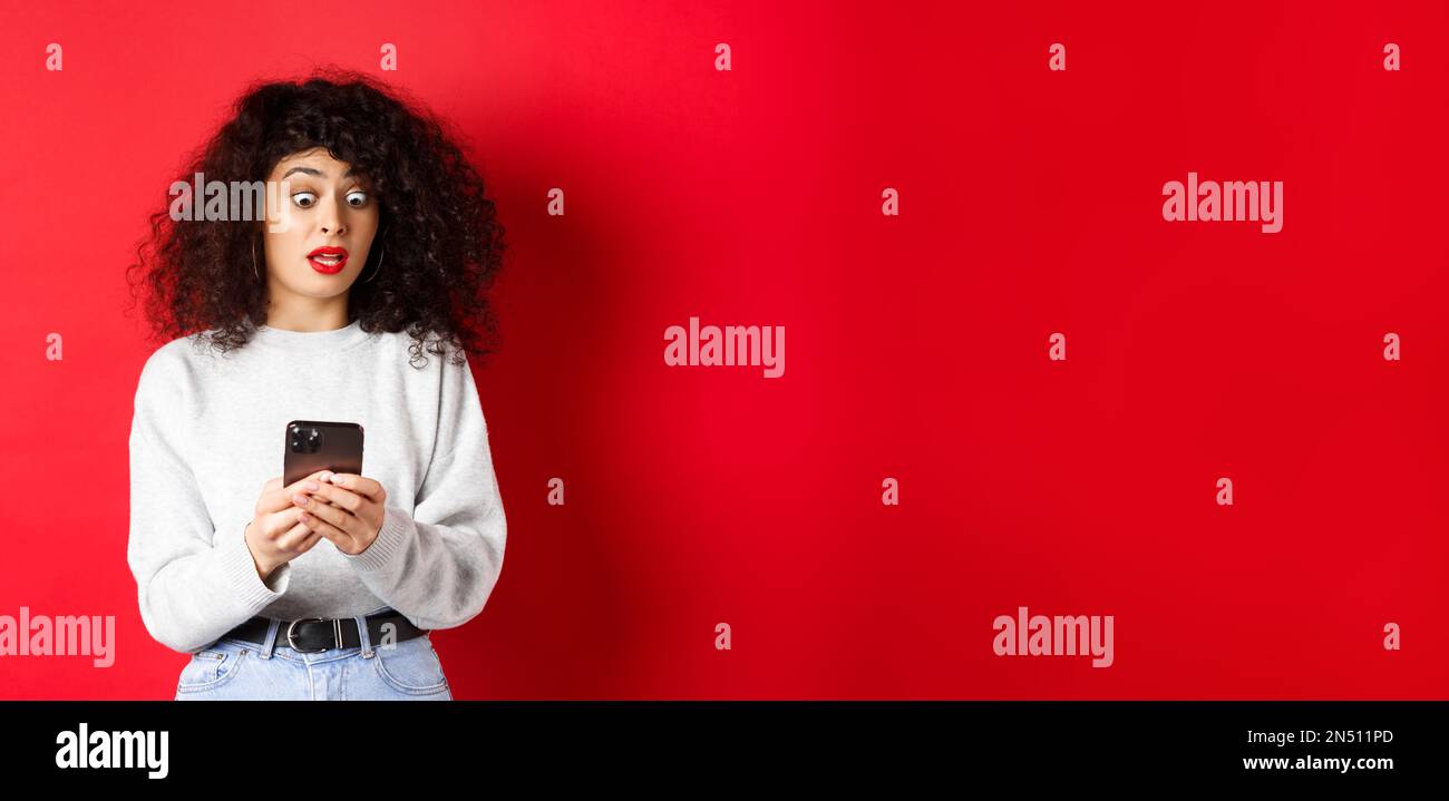 Shocked woman stare at smartphone screen with popped eyes, reading ...
