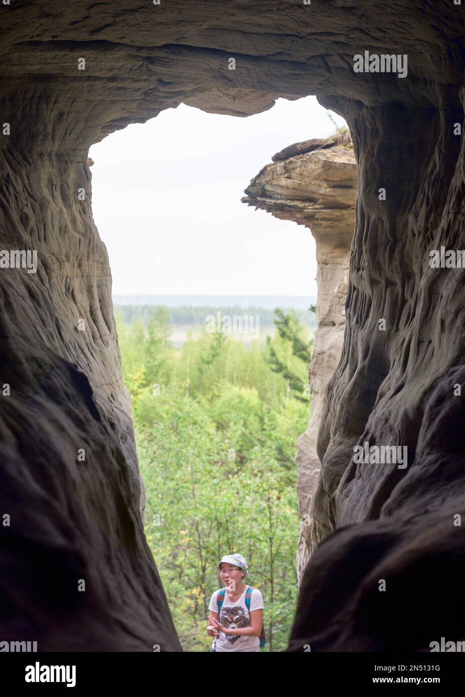 A young Yakut girl cautiously looks into a dark clay cave on the ...