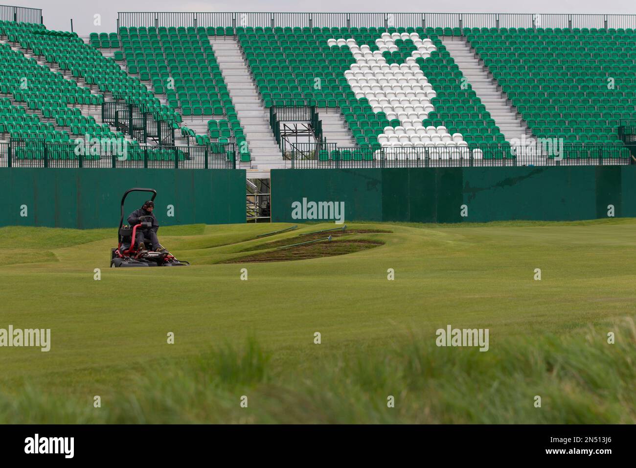 A greenkeeper mows the grass on the 18th green at Royal Liverpool Golf ...