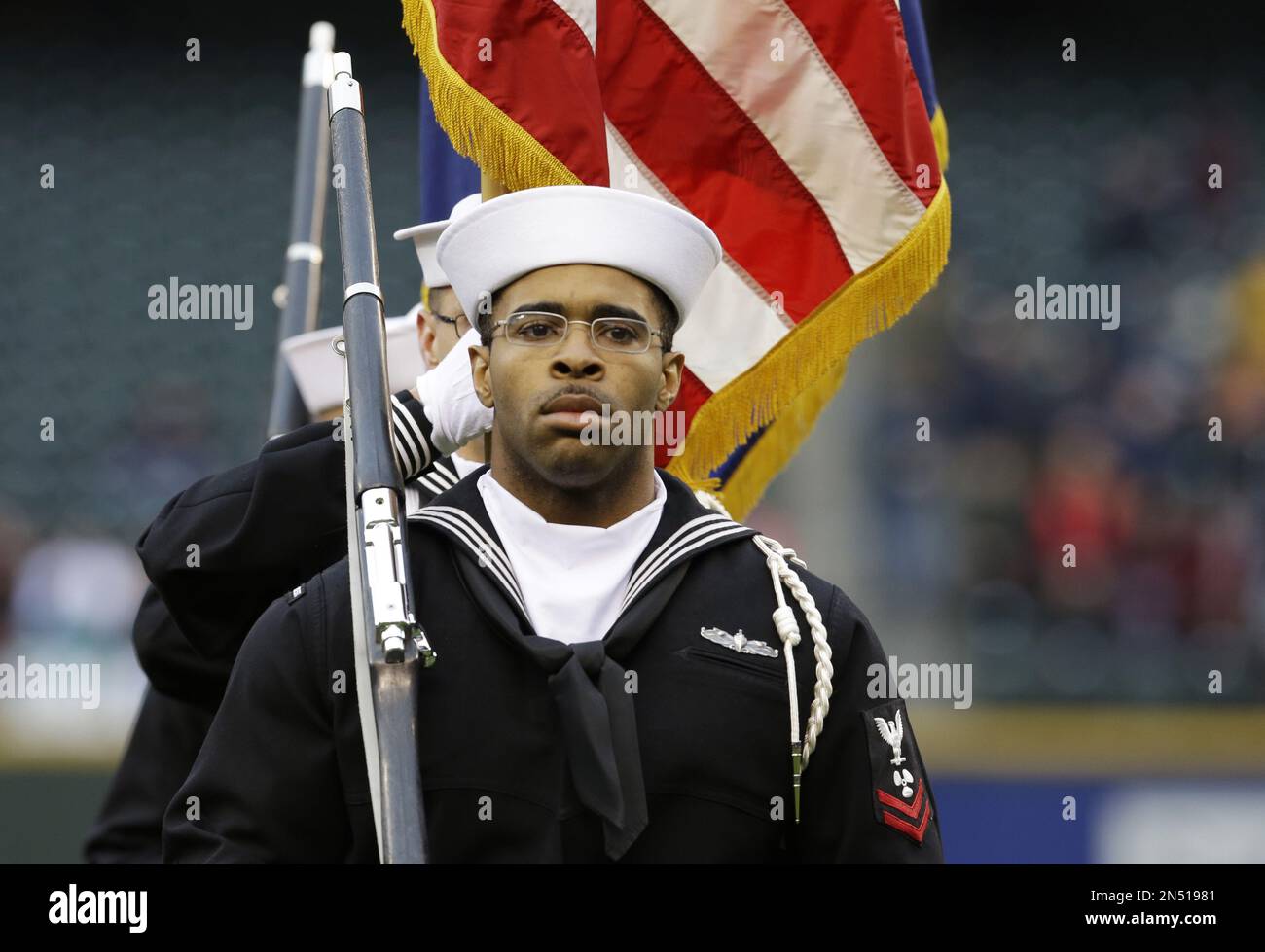 Members of a U.S. Navy color guard walk with the U.S. flag after the ...
