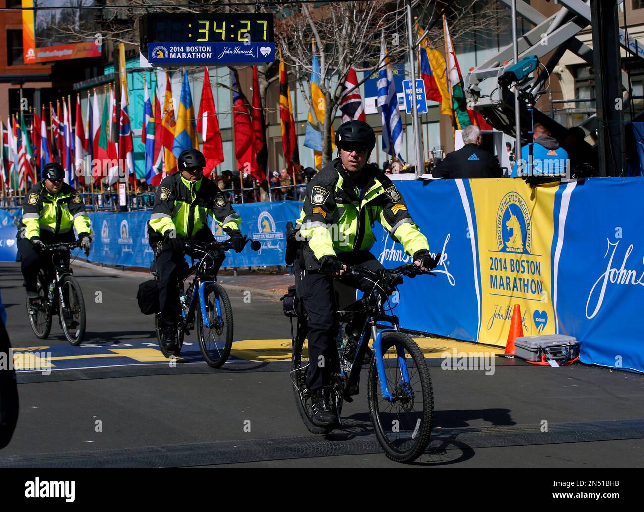 Boston Police officers on bicycles ride across the finish line before ...