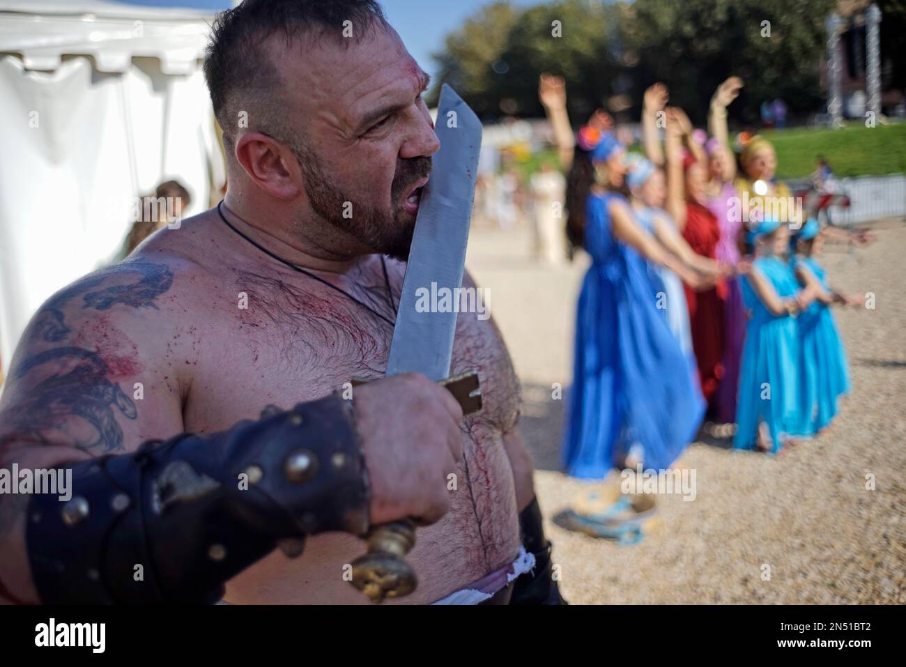 A performer dressed in traditional ancient Roman costume bites his ...