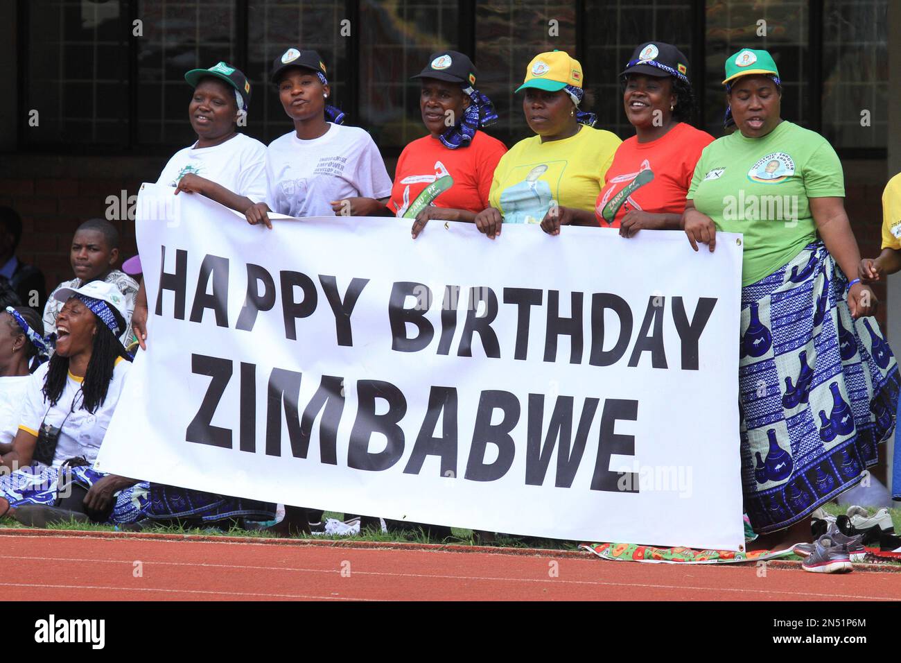 Women hold a banner with a birthday message for Zimbabwe, while waiting ...