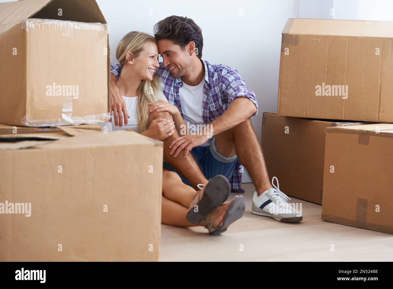 Creating a life together. A happy young couple cuddling while sitting ...