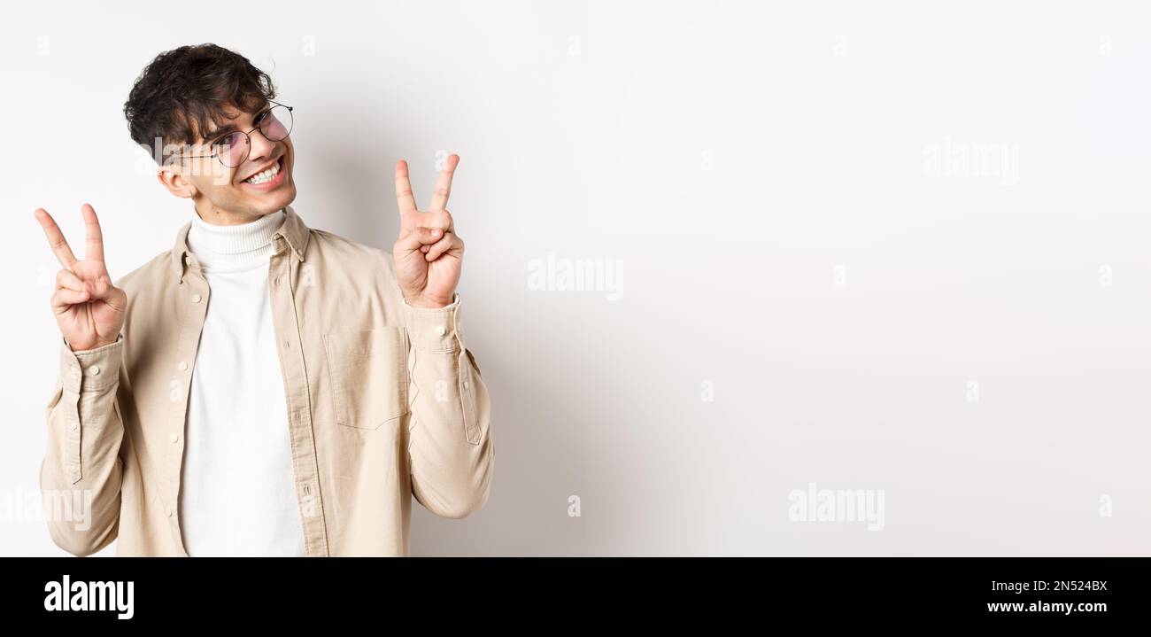 Real people. Handsome hipster guy in glasses showing peace gestures and ...