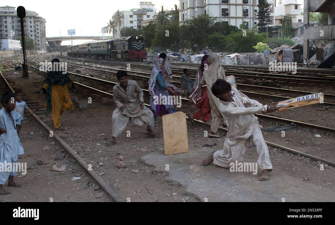 Pakistani boys play cricket on a railway track in the slums of Karachi ...