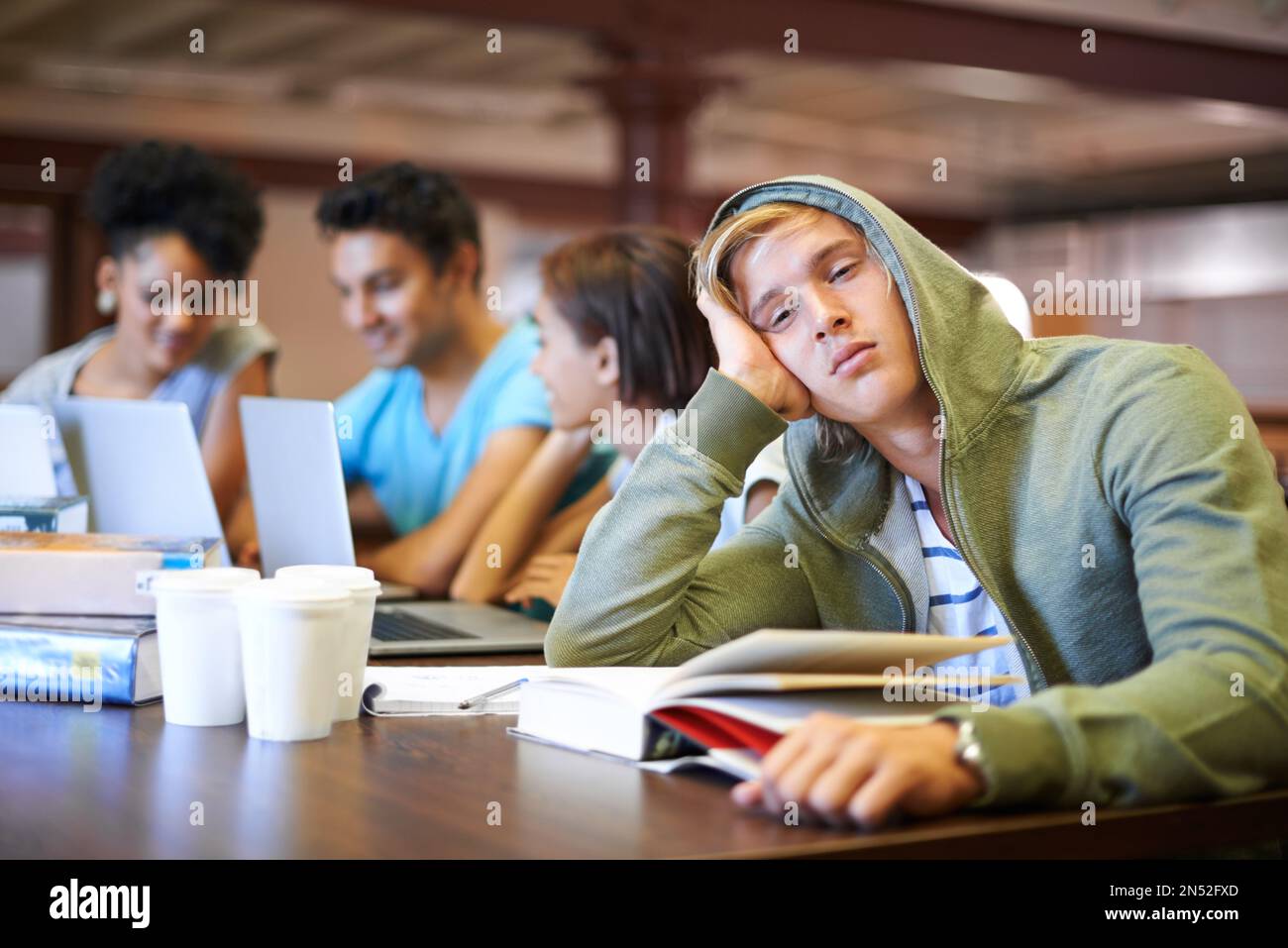 School is lame. A young student looking bored in his study group Stock ...