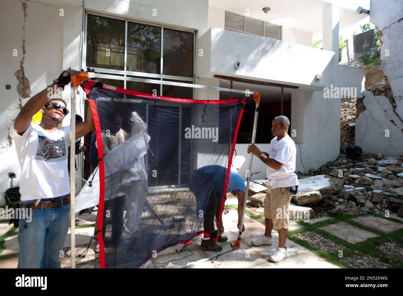 Crew members work on the set of the film "Murder in Pacot" at a home ...