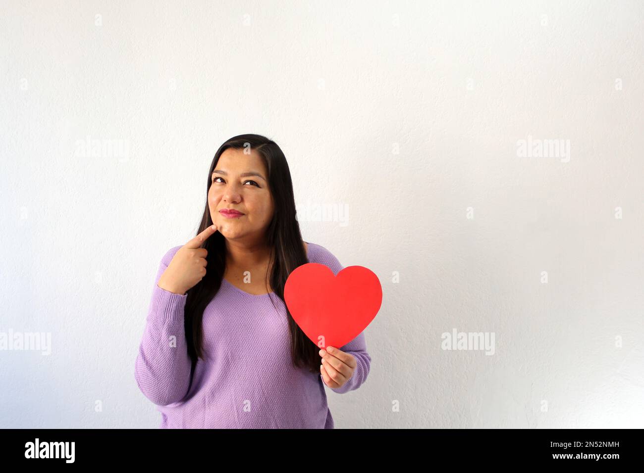 Latin adult woman with lila sweater with a big red heart shows her ...