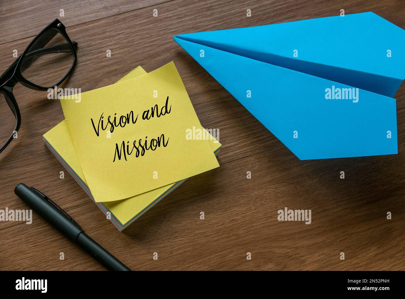 Selective focus of glasses, pen, paper plane and yellow memo note ...