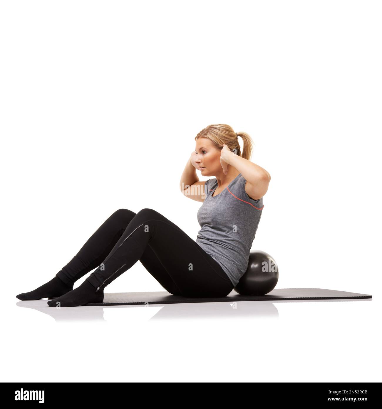 Her goal is a toned tummy. A young woman doing sit-ups on an exercise ...