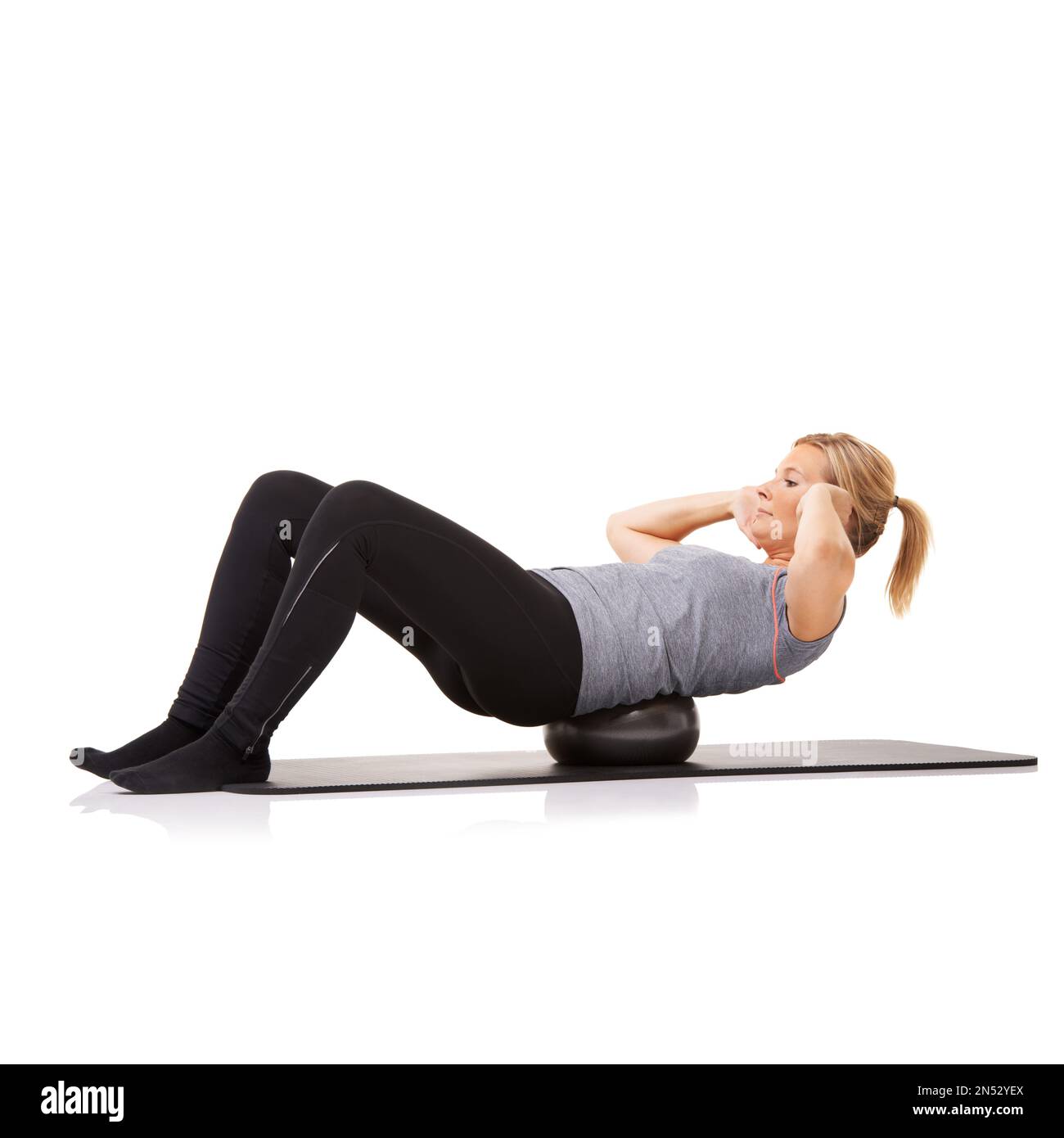 Balance And Sit Ups A Young Woman Doing Sit Ups On An Exercise Ball While Isolated On A White