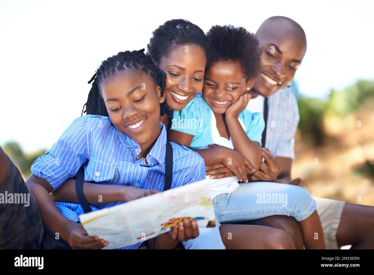 I think we are here. a happy-looking family looking at a map while out ...