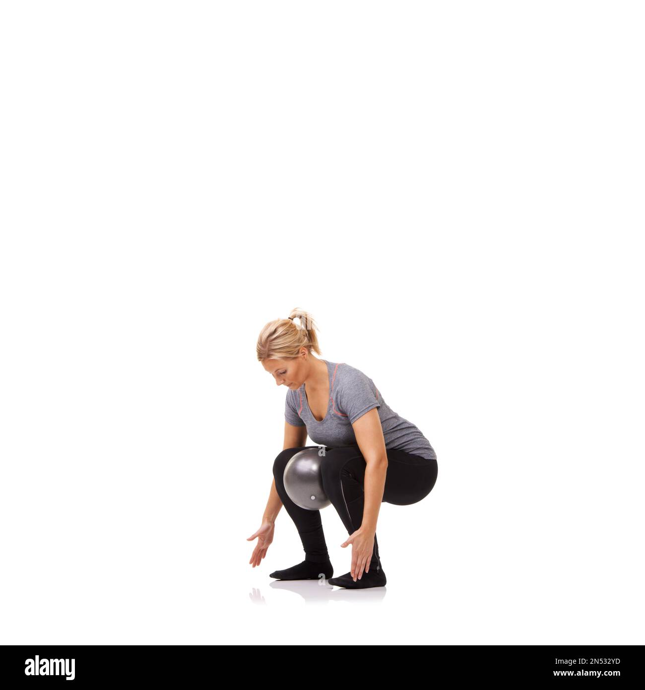 Squatting with a weighted exercise ball. A pretty young woman working ...
