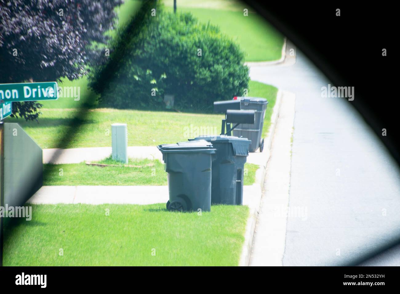 Window view outdoors neighborhood lawns grass and trash cans down the ...