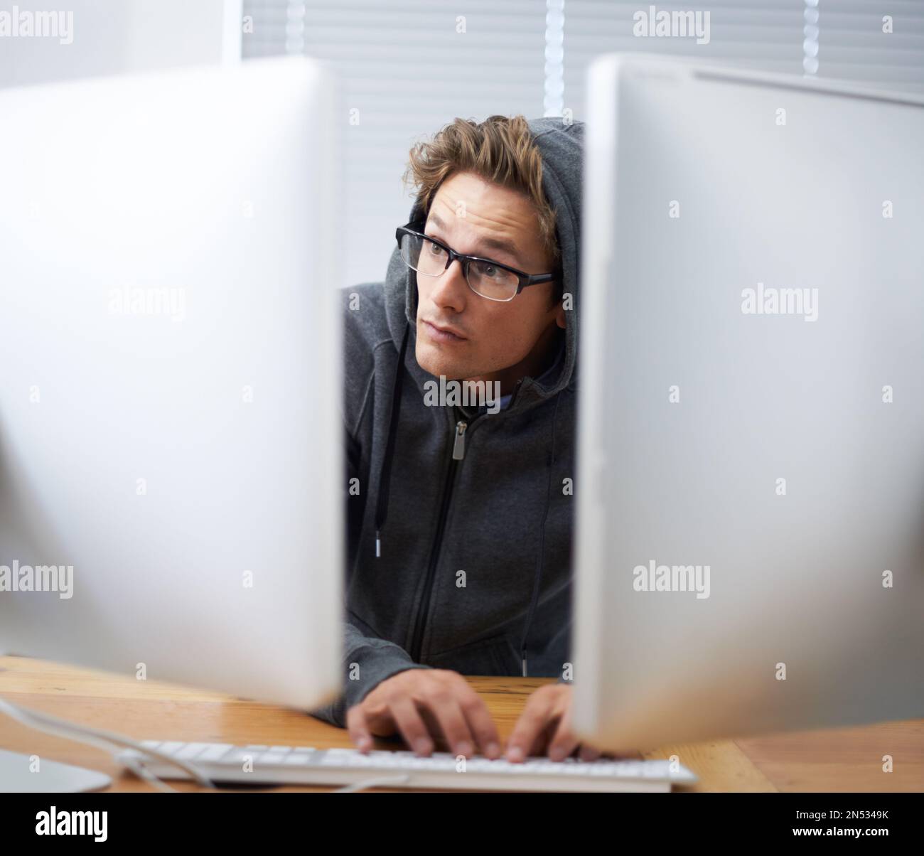 Works squeezing every bit of energy. A young hacker wearing a hoodie ...