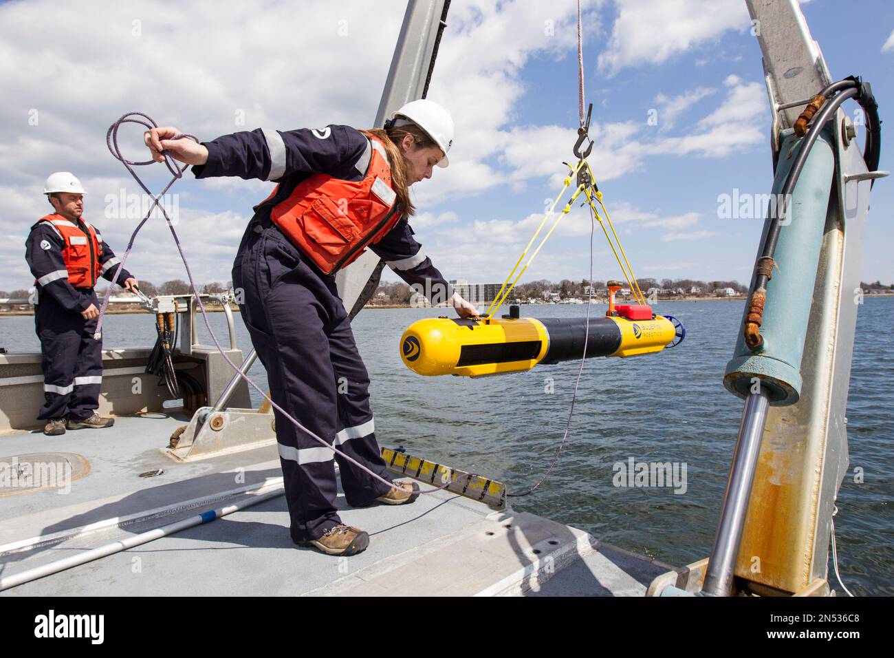 A submarine built by Bluefin Robotics is lowered into the water by ...