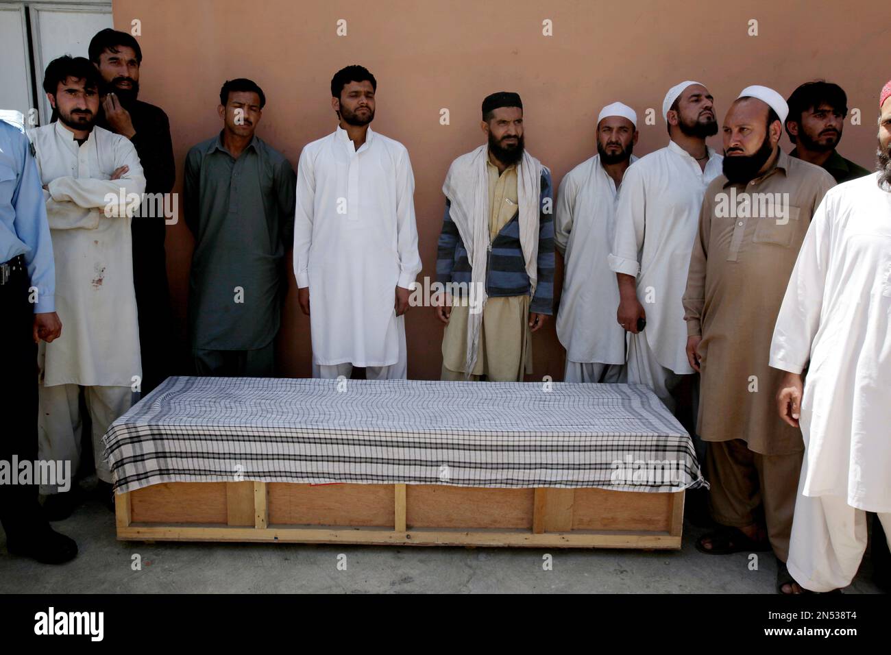 Pakistanis stand in front of the casket of their relative a victim of a ...