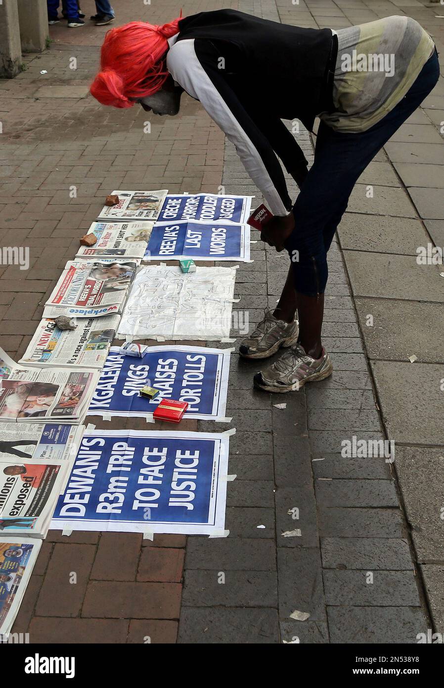 A man dressed as a clown reads newspaper headlines outside the court ...