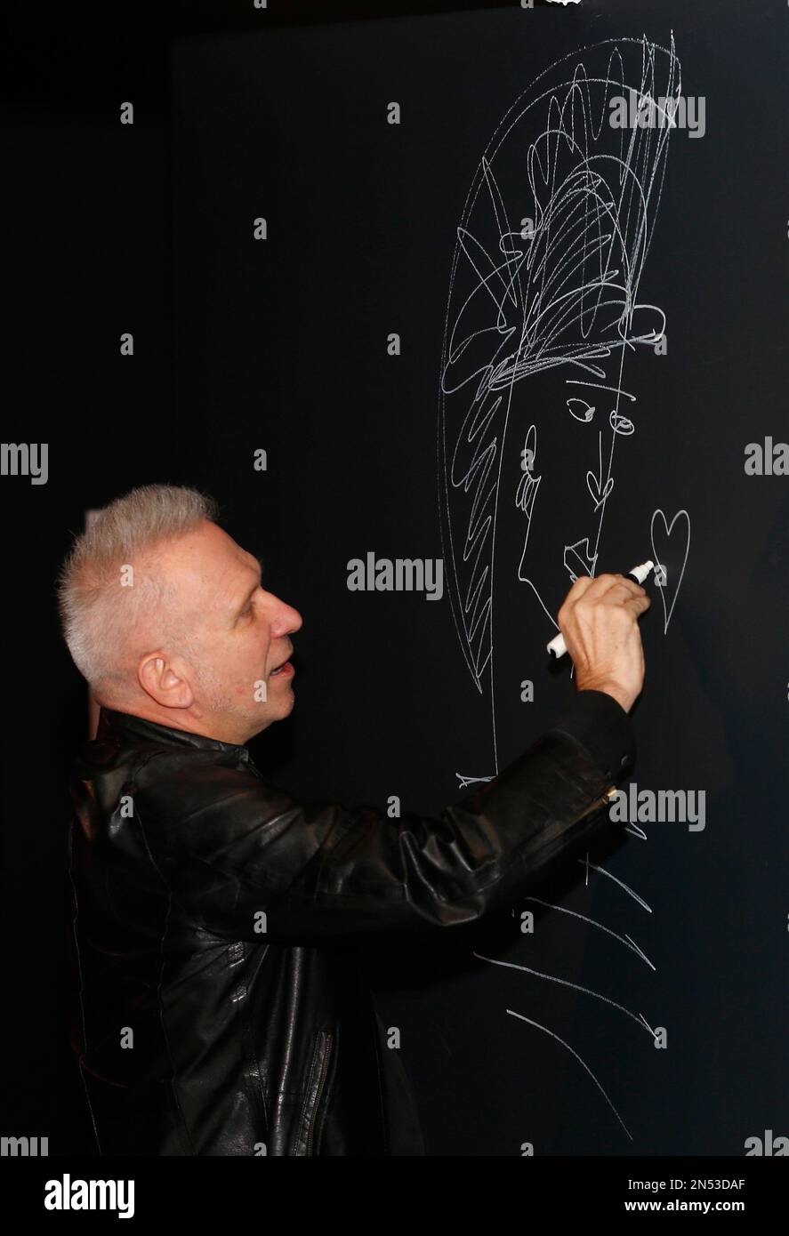 French couturier Jean Paul Gaultier signs on the wall to launch of his ...