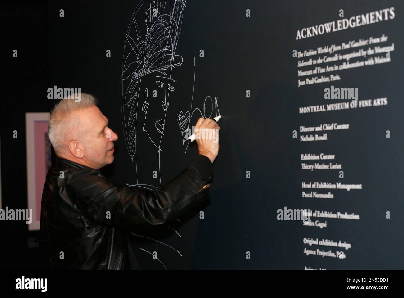 French couturier Jean Paul Gaultier signs on the wall to launch his ...