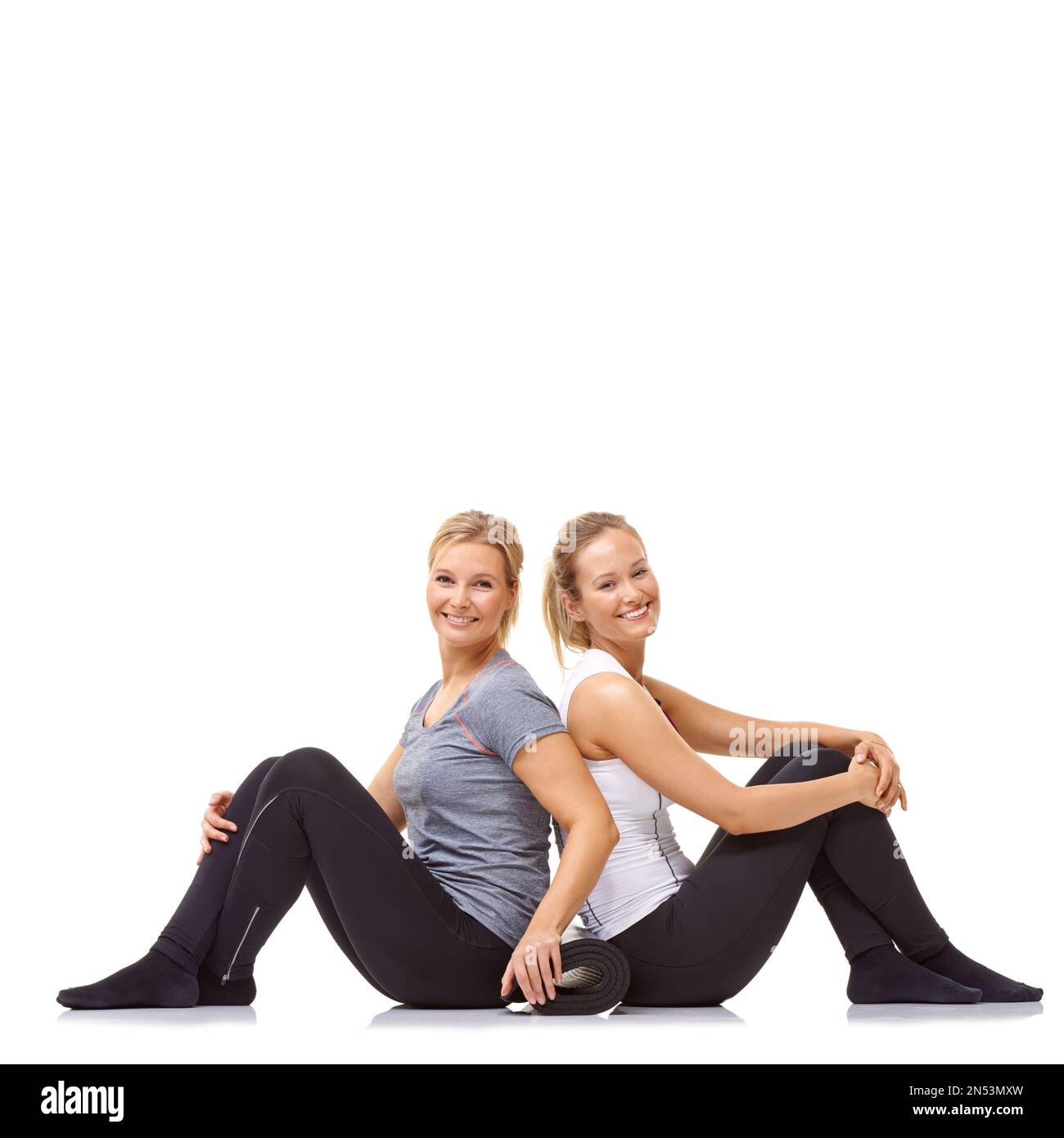 Gym buddies. Two gym friends sitting back to back while isolated on a ...