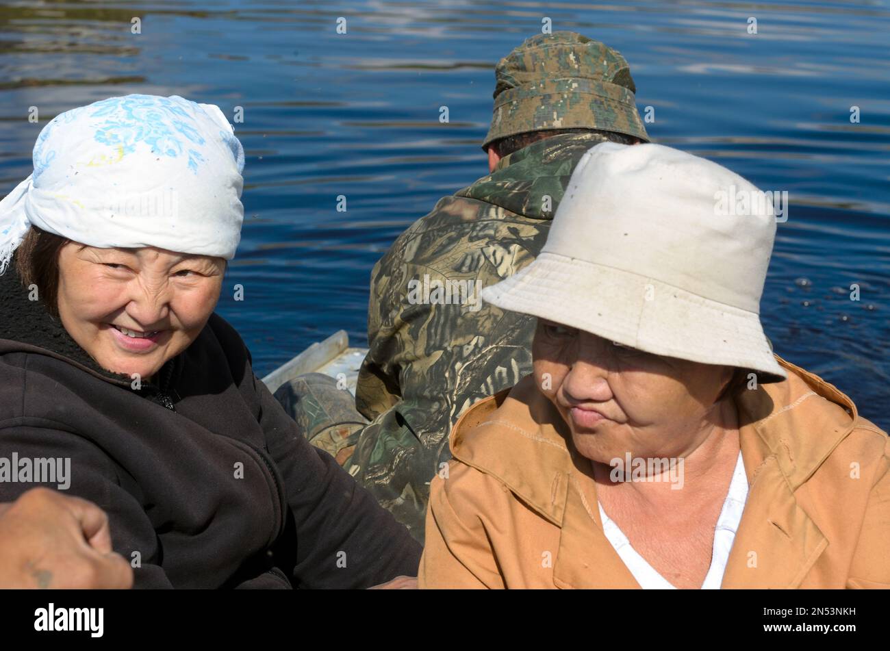 Faces joyful and sad two Yakut women sitting in a boat floating on the ...