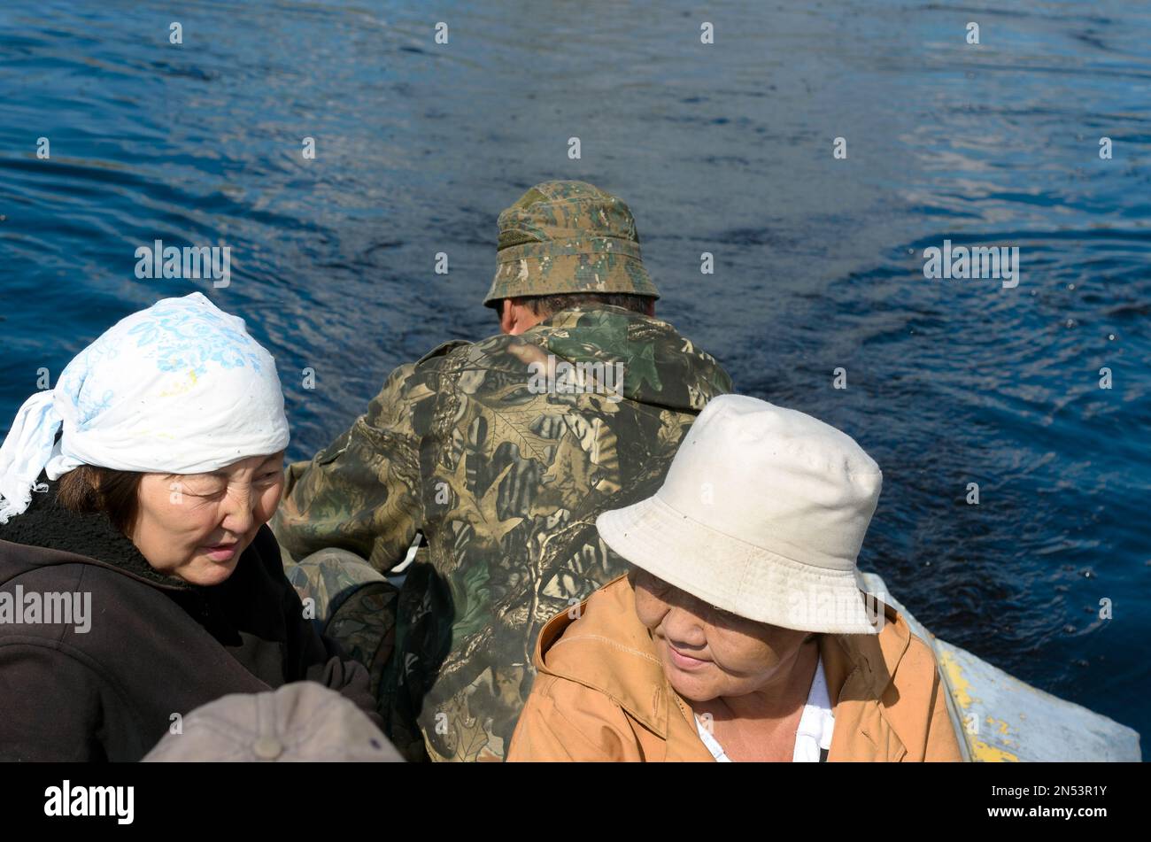 Two adult females Yakuts sitting in the back of the boat, floating down ...