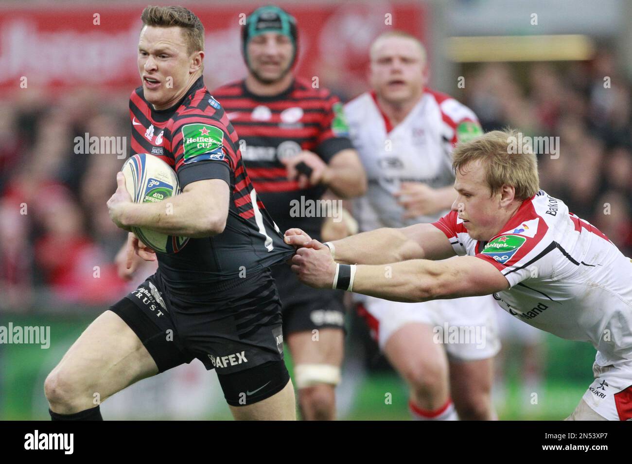 Saracens' Chris Ashton, left, breaks through a tackle from Ulster's ...