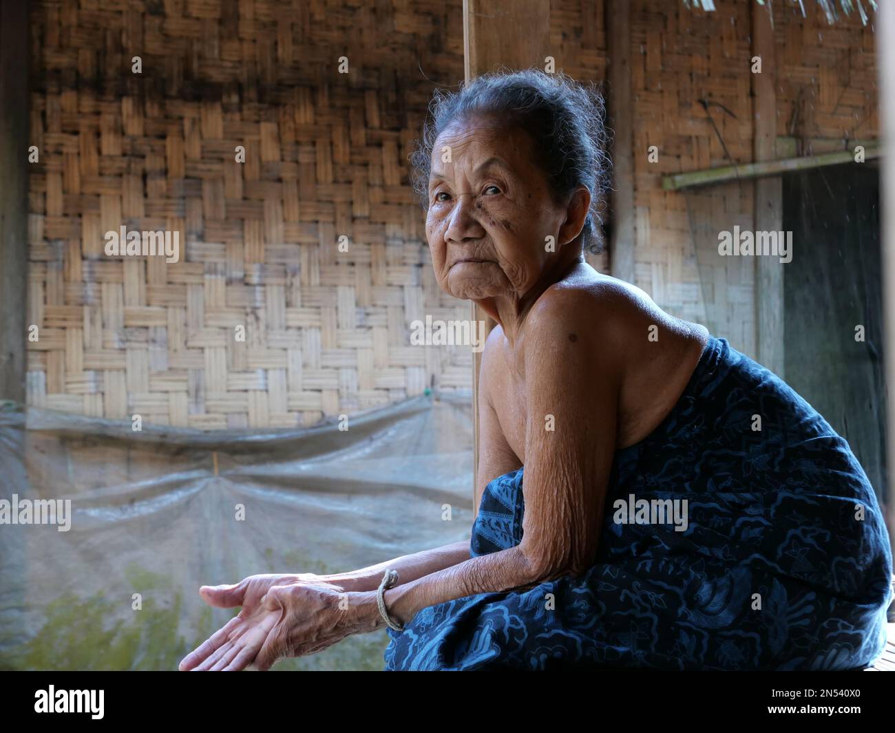 a photo of a grandmother sitting silently wearing only cloth clothes ...