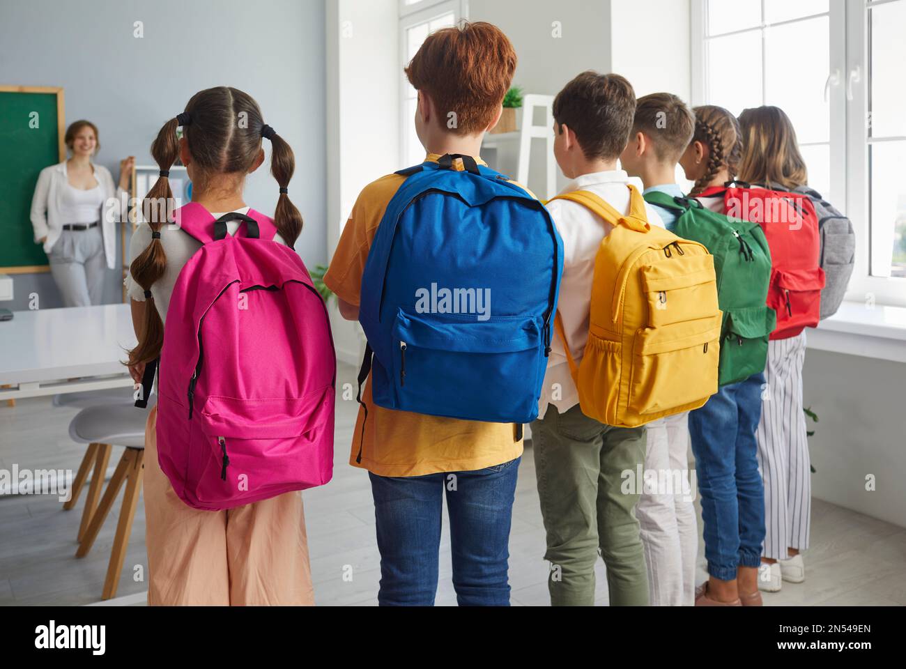 Back view of a group of school children with backpacks standing in the ...