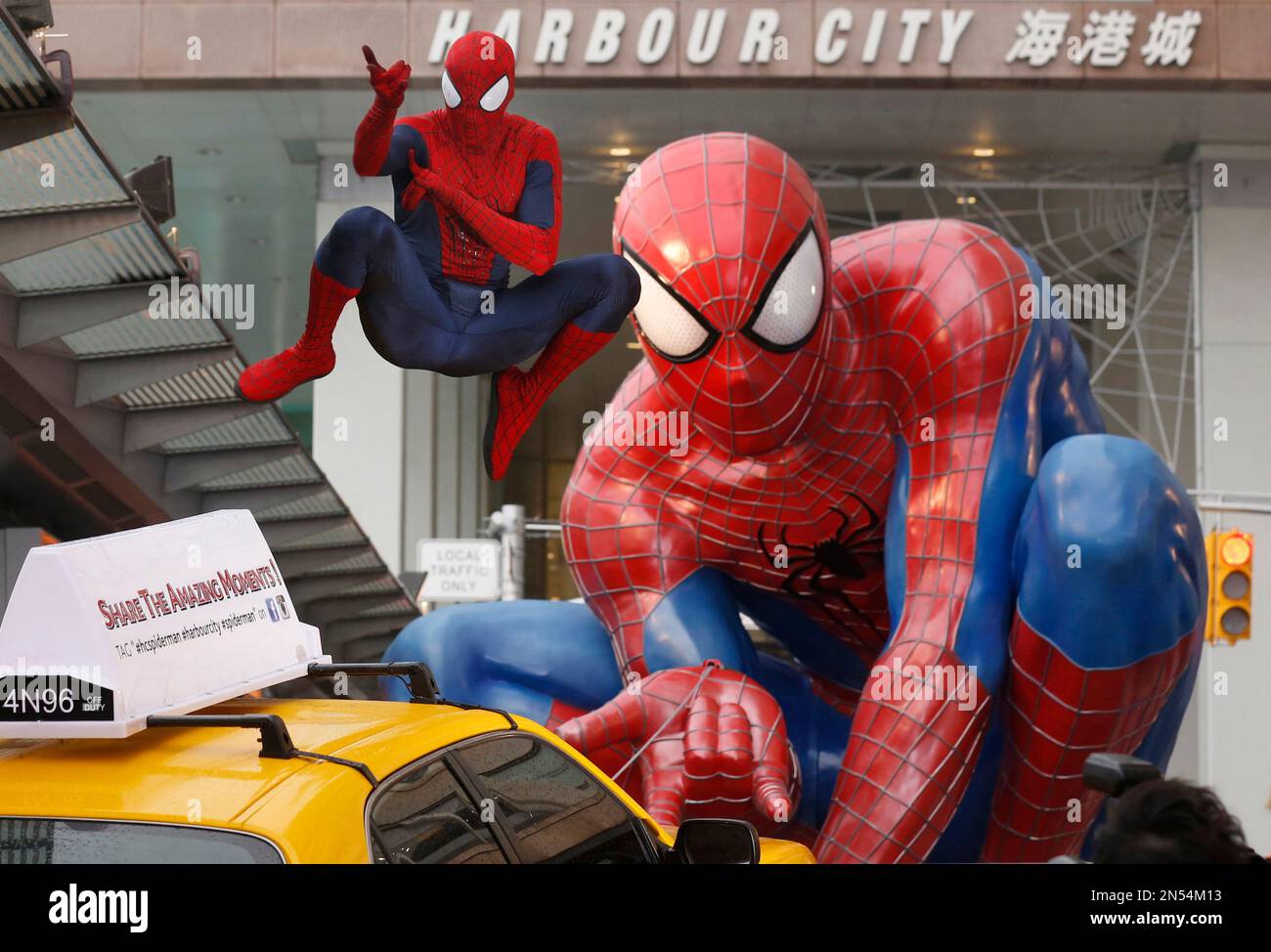 A stuntman, left, jumps in front of the Spider man statue to promote ...