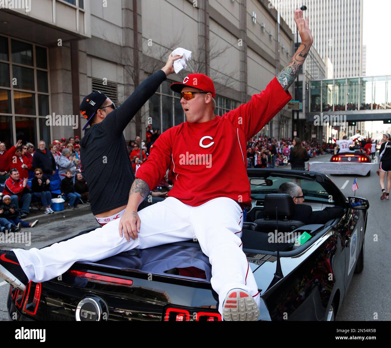 Cincinnati Reds starting pitcher Mat Latos rides on the back of a car ...