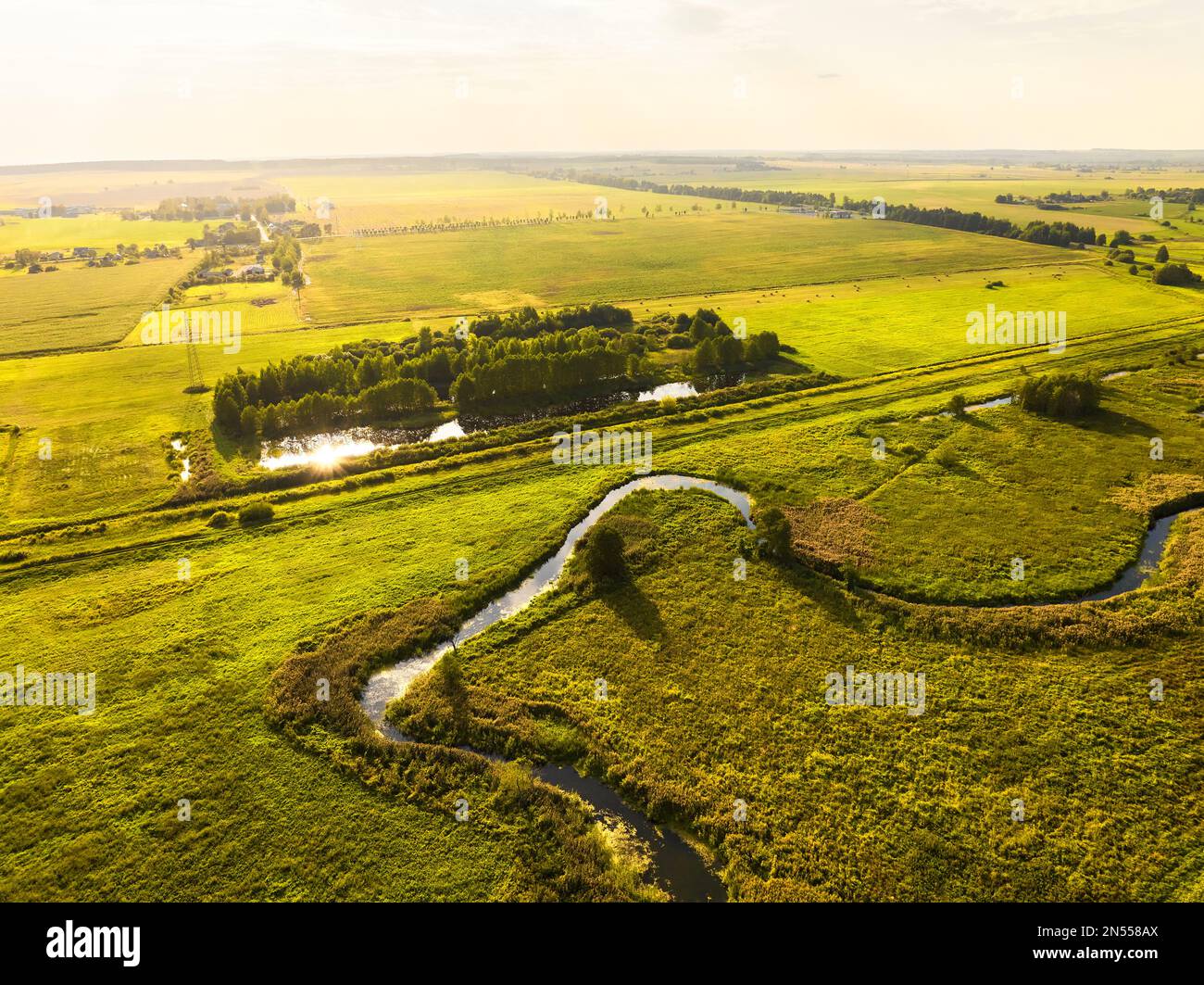 Small river flows among fields illuminated by sunset light Stock Photo ...