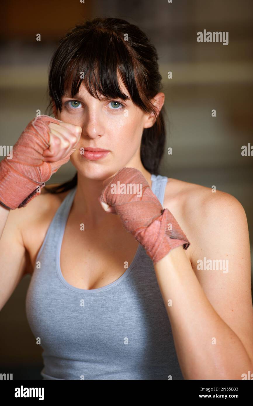 At the ready. Portrait of a determined female boxer standing ready to ...