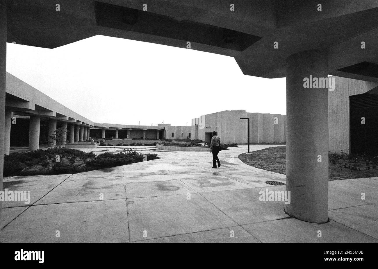 An inmate stands on a patio outside a cell block, background, at the ...